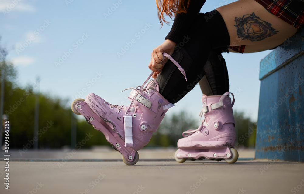 Aggressive inline skater girl tying laces on modern roller blades in a ...