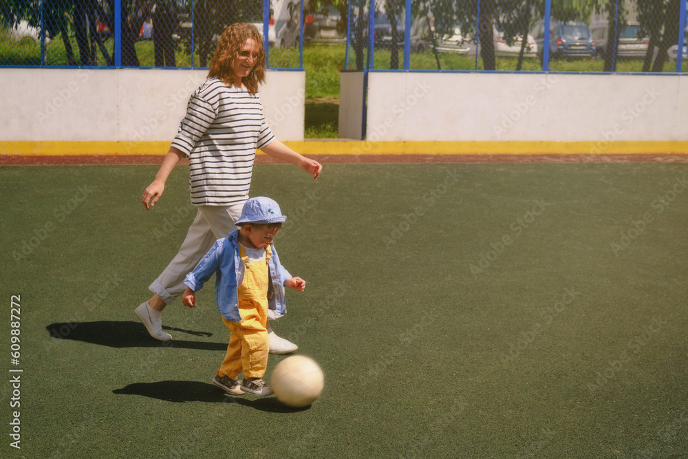 The child and woman mother is having fun kicking the soccer ball around ...