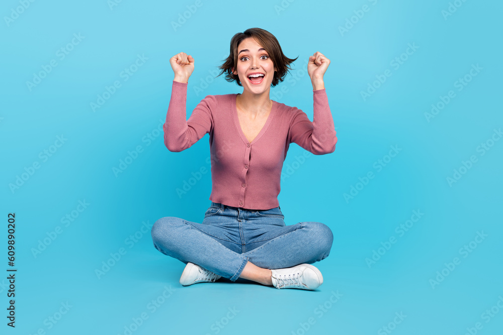 Full body portrait of overjoyed cheerful lady sit floor raise fists ...