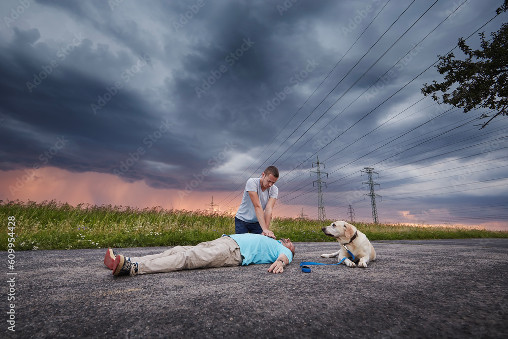 Dramatic resuscitation on rural road. Young man provides first aid to ...