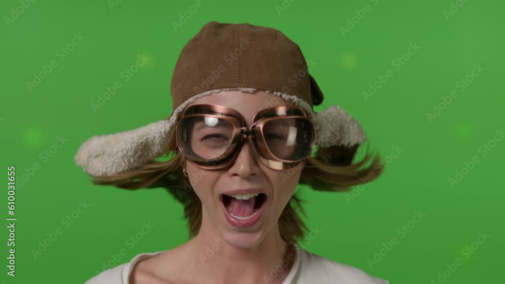 Close-up of a girl's face in a retro pilot's hat blown by a strong wind ...