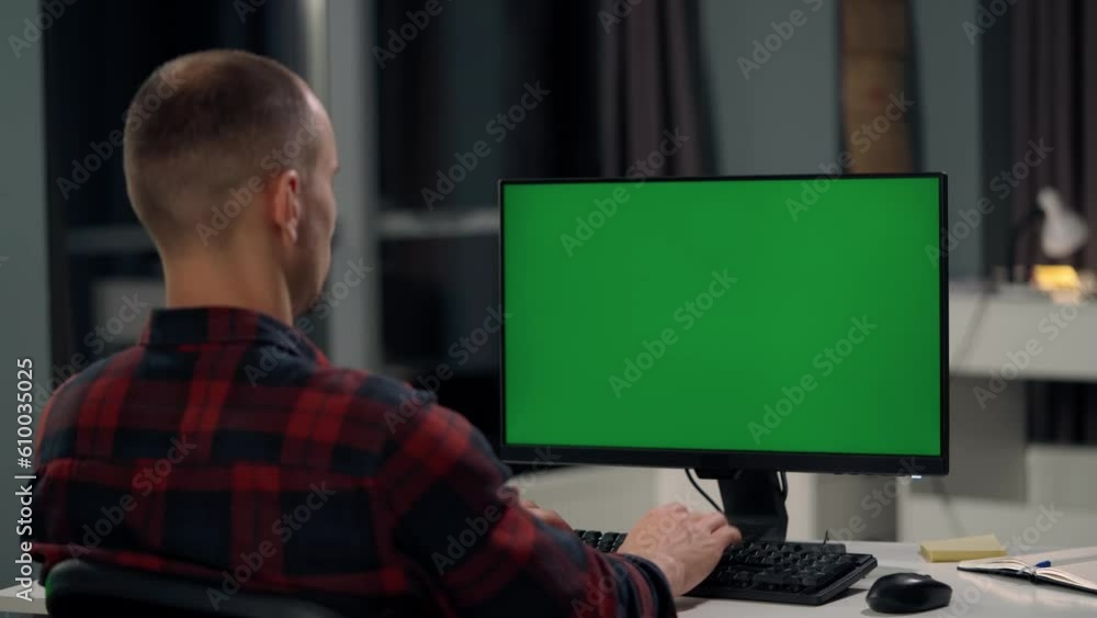 Young Man Working At Computer With Green Mock Up Screen in Home. Close ...