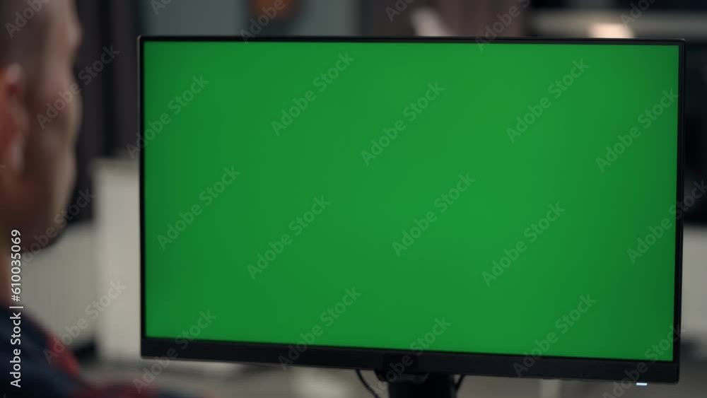 Young Man Working At Computer With Green Mock Up Screen in Home. Close ...