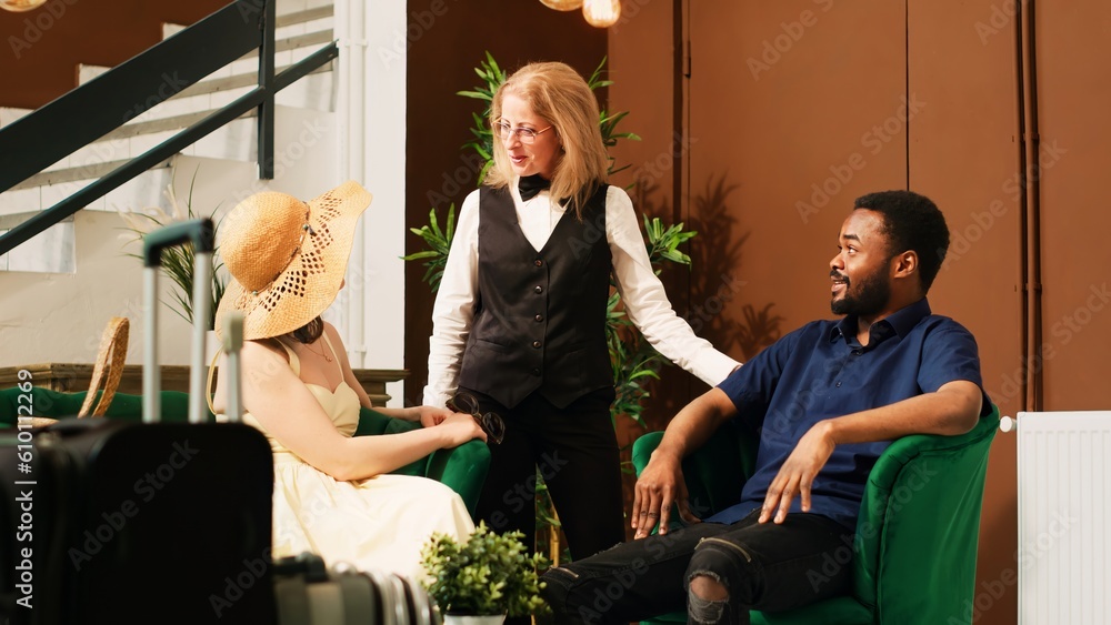 Resort employee chatting with people in lobby, couple waiting to do ...