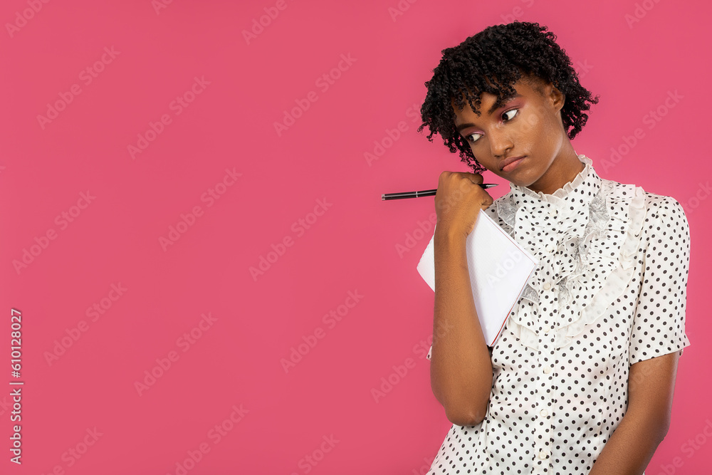young brunette woman with curly hair, holding a notebook is against the ...