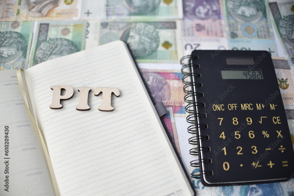 Kalkulator, kalendarz i napis PIT, w tle banknoty o roznych wartosciach ...
