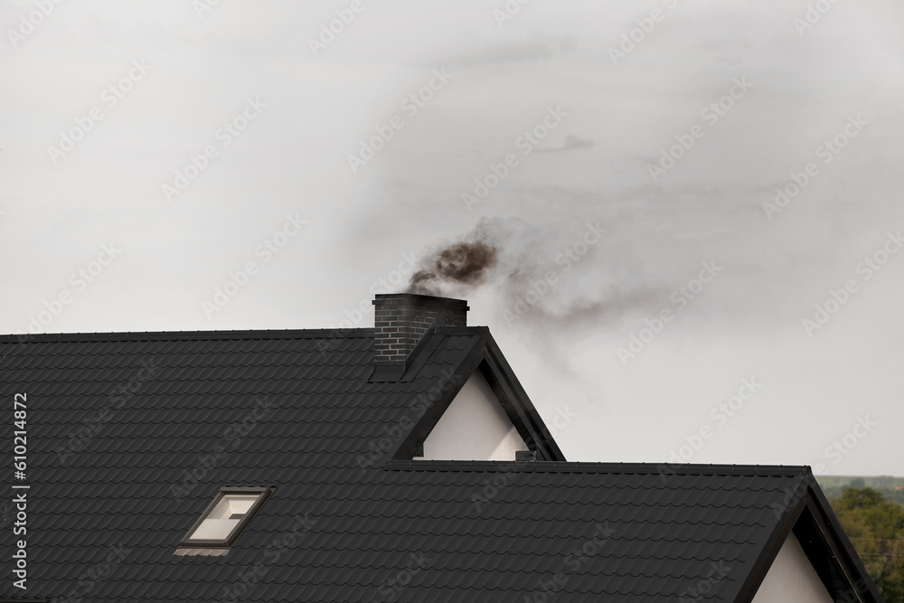 Foto de Black smoke comes out of a modern house chimney. The concept of ...