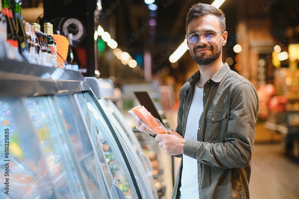 Handsome young man check the fridges for frozen food in the supermarket ...