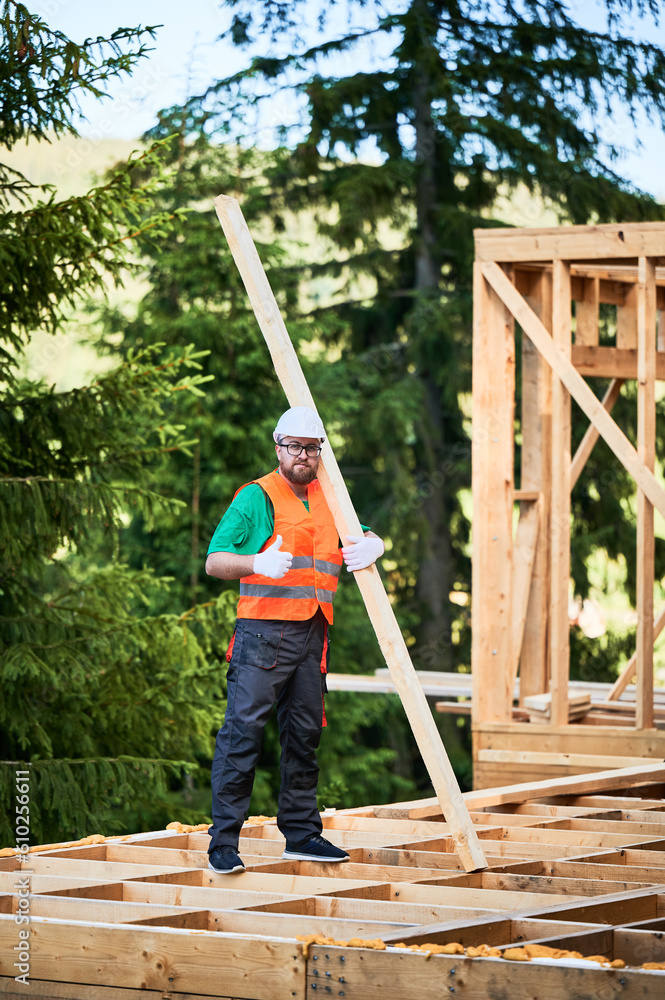 Carpenter builds wooden frame house near the forest. Bearded man with ...