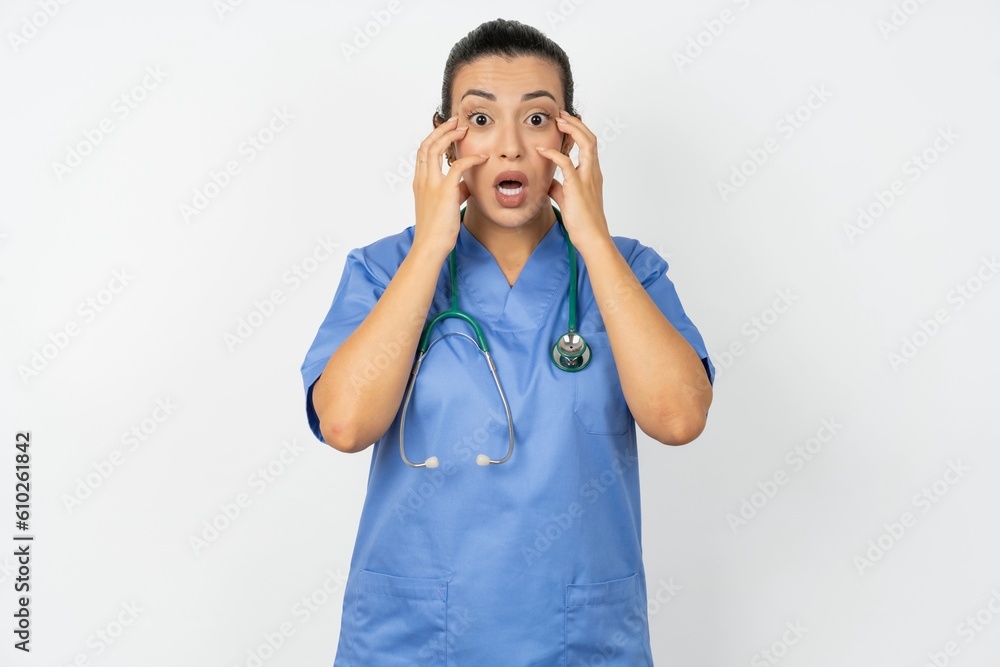 Stupefied Beautiful doctor woman standing over white studio background ...