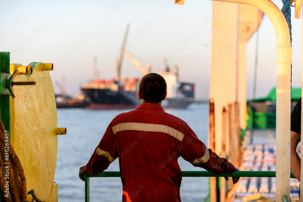 Seaman in red working overall and orange helmet on deck. Working at sea ...