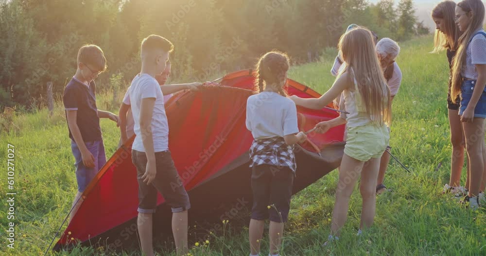 Back view of kids setting up, raising red tent, organizing campsite ... Back view of kids setting up, raising red tent, organizing campsite ...