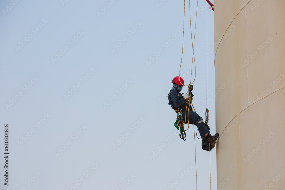 Male worker rope access industrial working at height tank oil wearing ...