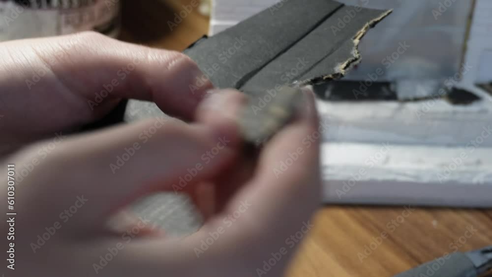 A person tears a piece of black cardboard, revealing the texture of ...