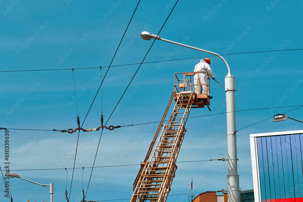 Painter in crane bucket paint street light pole. Worker in aerial ...