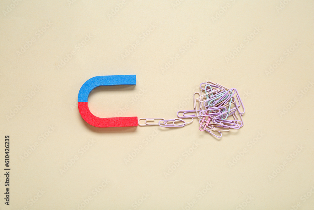 Magnet attracting paper clips on beige background Stock Photo | Adobe Stock