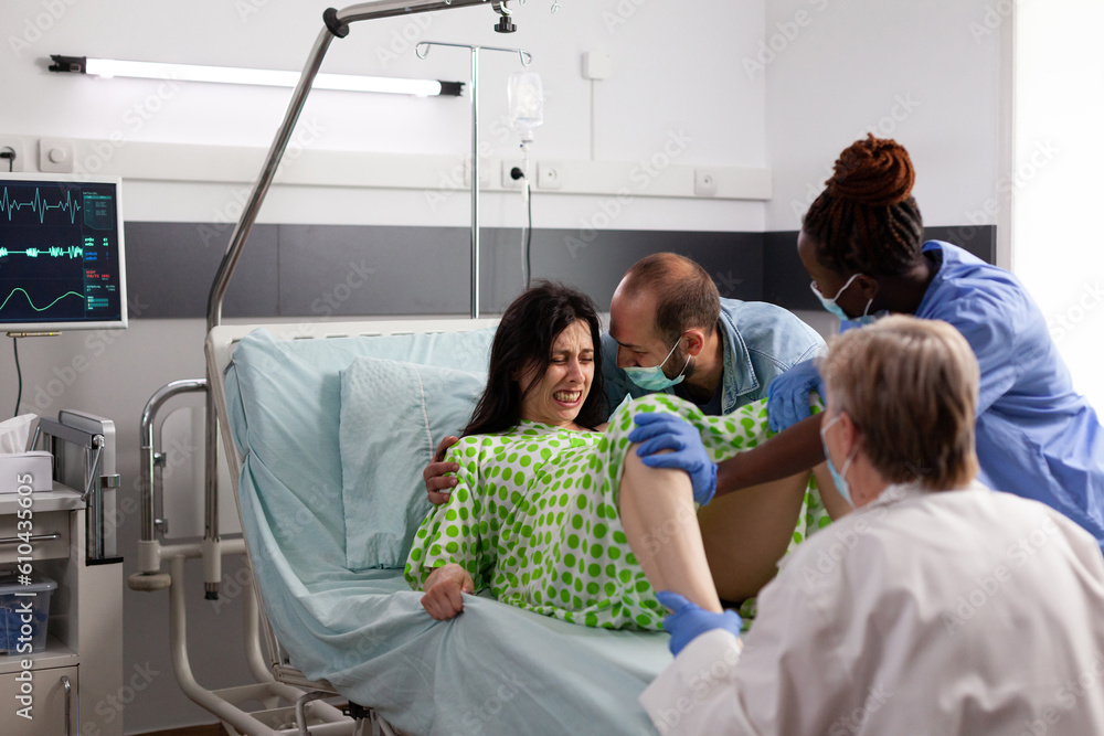 Foto de Diverse medical team delivering baby for woman with painful ... Foto de Diverse medical team delivering baby for woman with painful ...