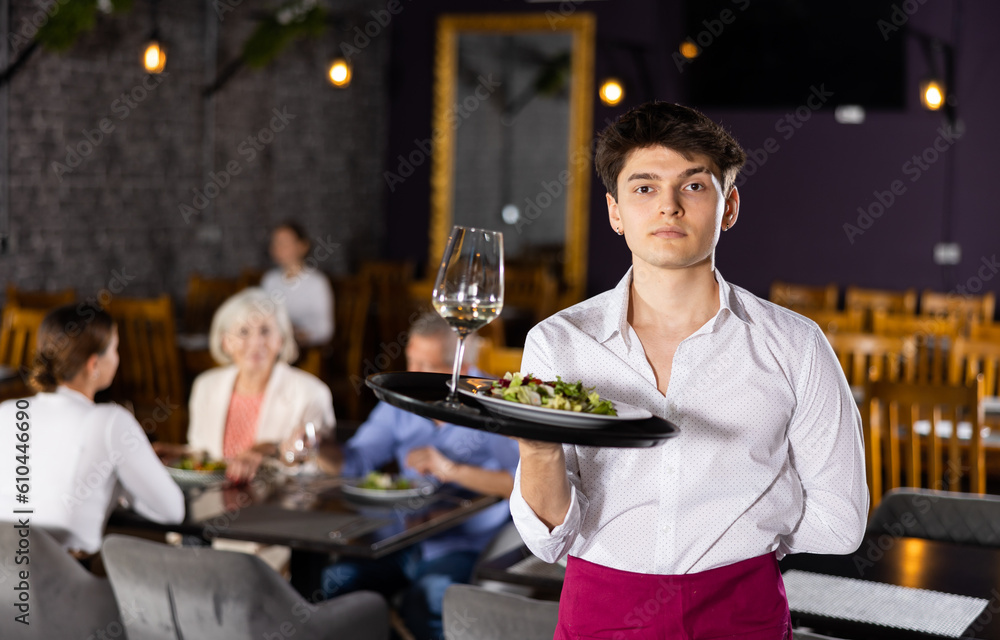 Young waiter guy is standing with order tray in spacious guest room in ...