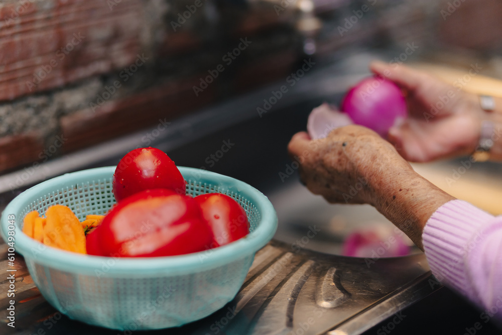Mujer latina, adulto mayor ,en la cocina , picando, cortando verduras ...