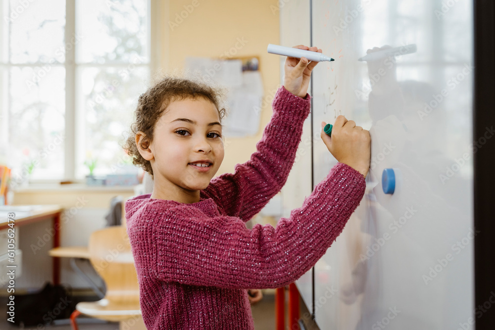 Portrait of smiling girl writing on whiteboard in classroom Stock Photo ...