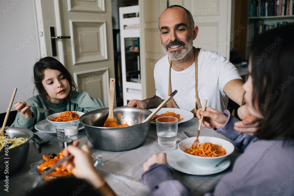 Happy father eating spaghetti with children at dining table Stock Photo ...
