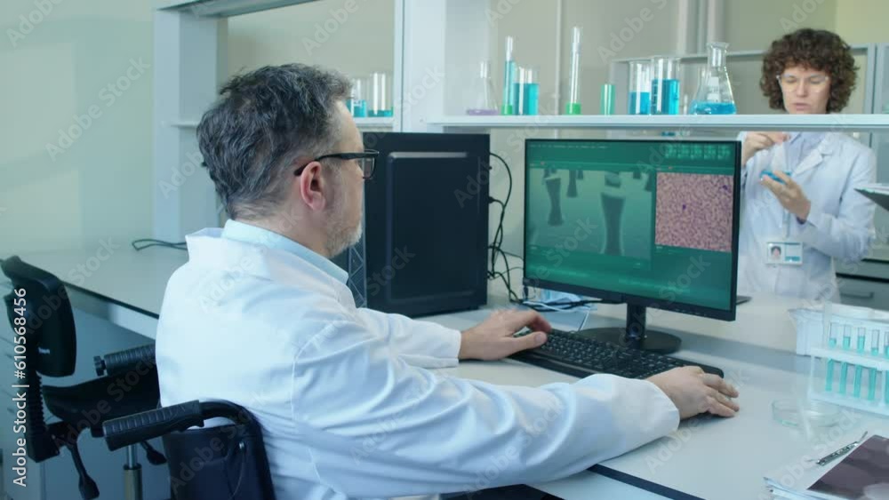Tilt shot of male senior professor using wheelchair to approach desk ...