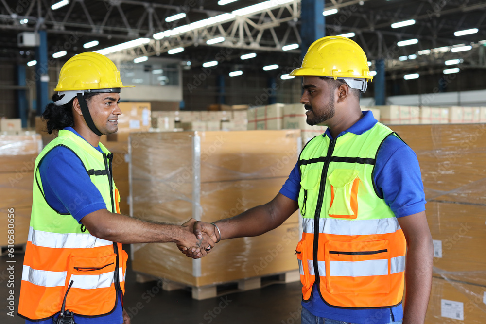 Happy smiling teamwork in hardhats and reflective jackets shaking hands ...