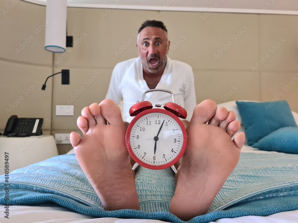 Oversleeping man holding alarm clock, waking up late for work and lying ...