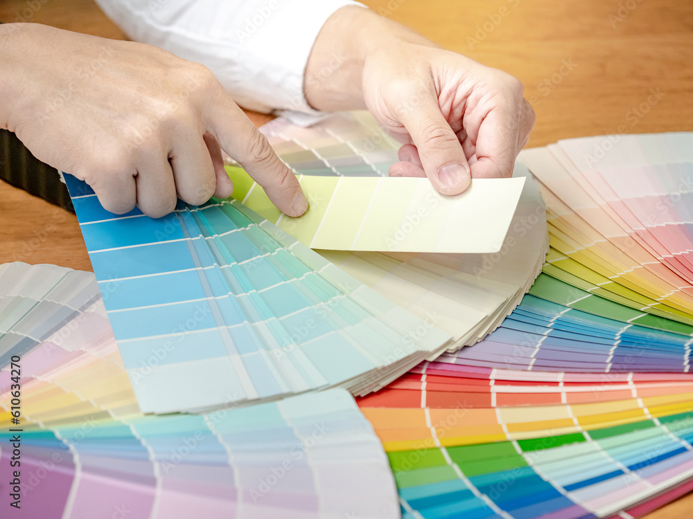 Foto de Designer hand choosing and pointing at color swatch samples ...