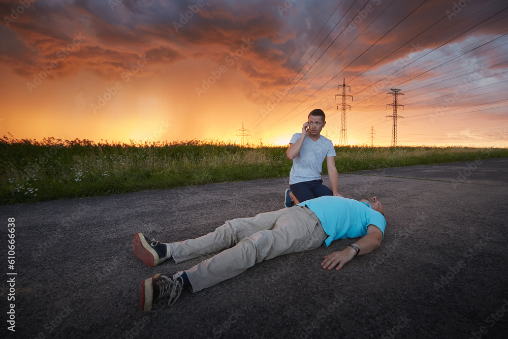 Young man calling emergency services for unconscious middle aged man ...