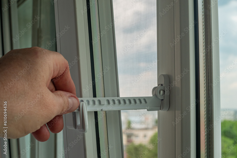 Close-up of a man's hand adjusting a window opening limiter. Window ...