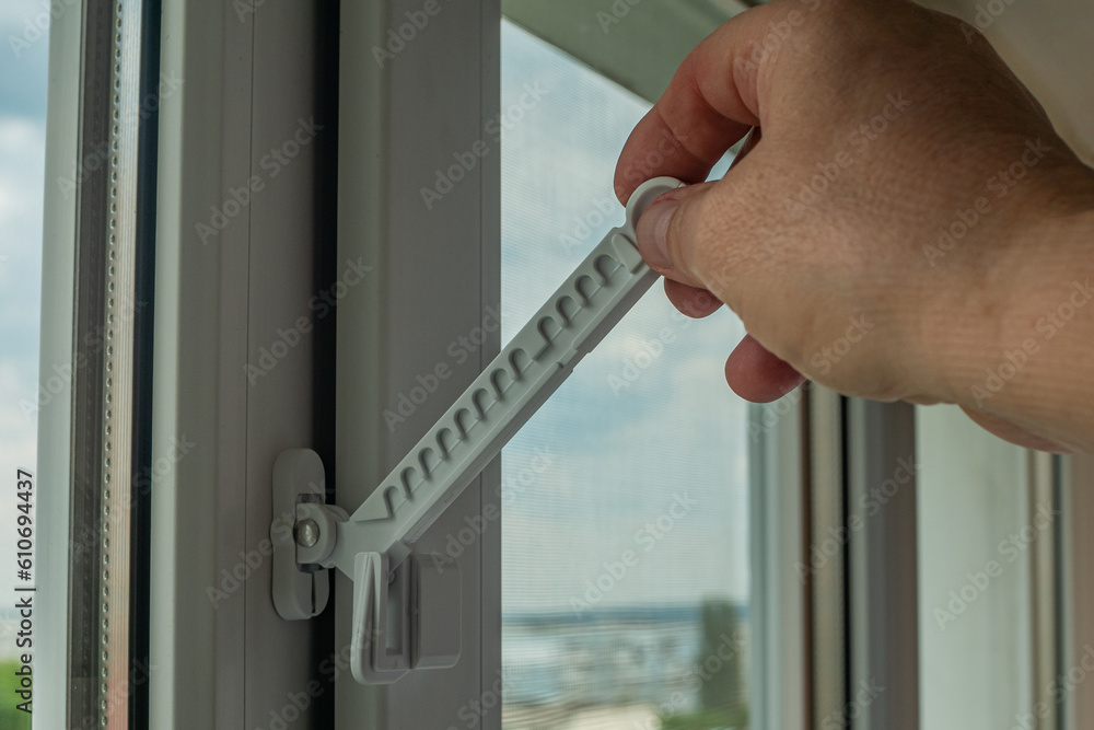 Close-up of a man's hand adjusting a window opening limiter. Window ...