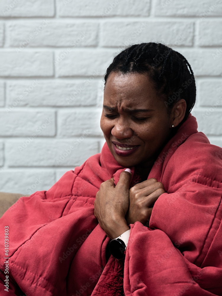 African American woman sitting at home wrapped in blanket crying ...