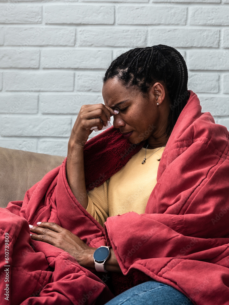 African American woman sitting at home wrapped in blanket crying ...