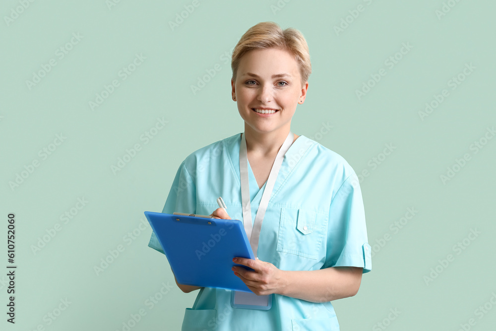 Female medical intern with clipboard on green background Stock Photo ...