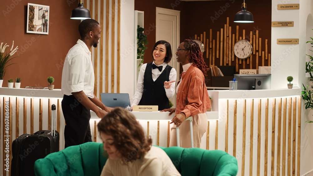 Friendly asian receptionist booking in tourists providing room access ...