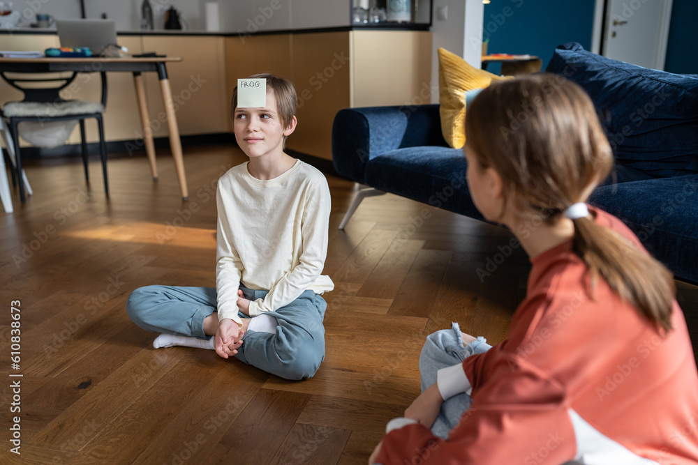 Smiling teen sister and child brother play together who am i guess ...
