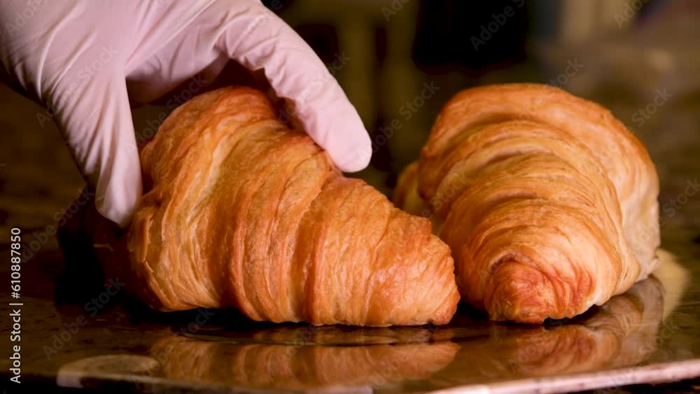 Close-up of a chef in gloves preparing a croissant chef's gloved hands ...