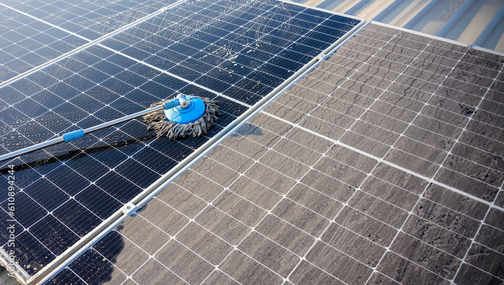 Technican using a mop and water to clean the solar panels that are ...