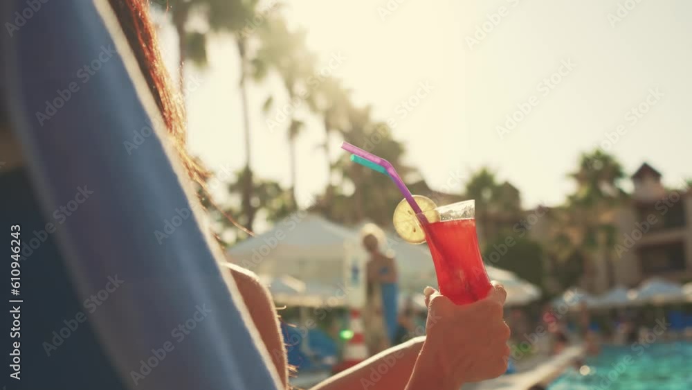 Woman sitting on beach chair and holding in hand drinking and stir ...