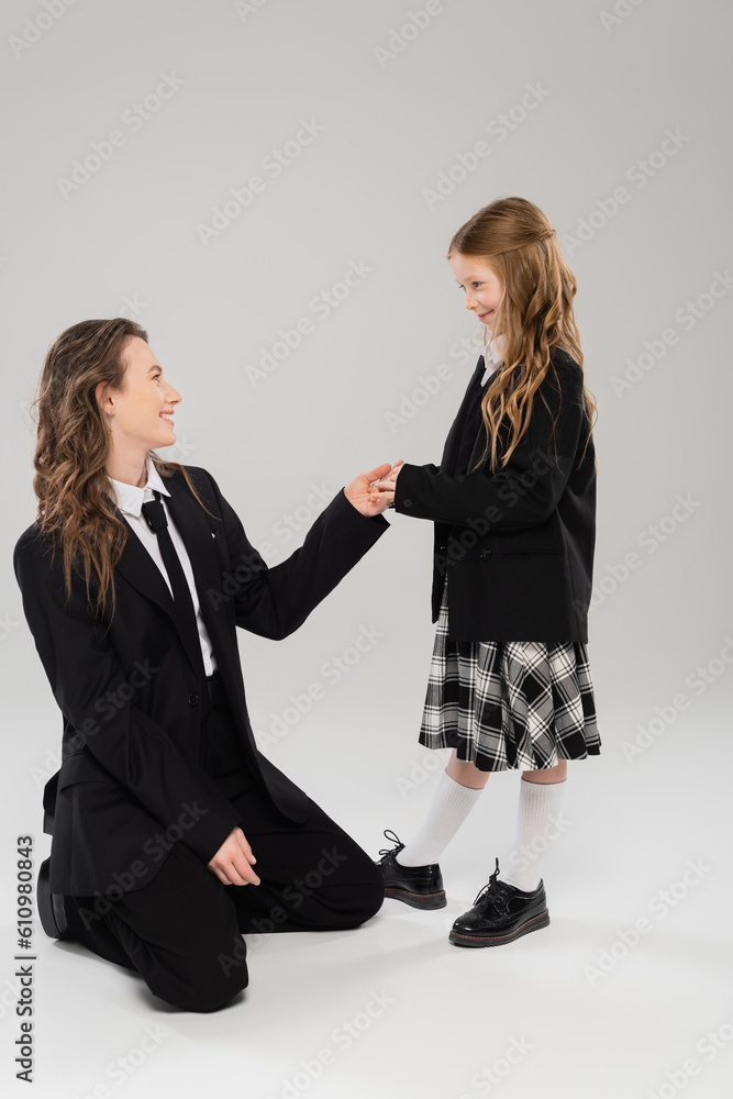 smiling schoolgirl holding hands with working mother, cheerful girl in ...