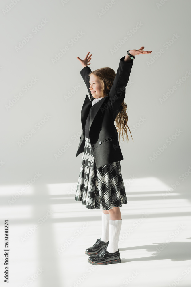 schoolgirl in uniform, cheerful preteen girl standing with raised hands ...