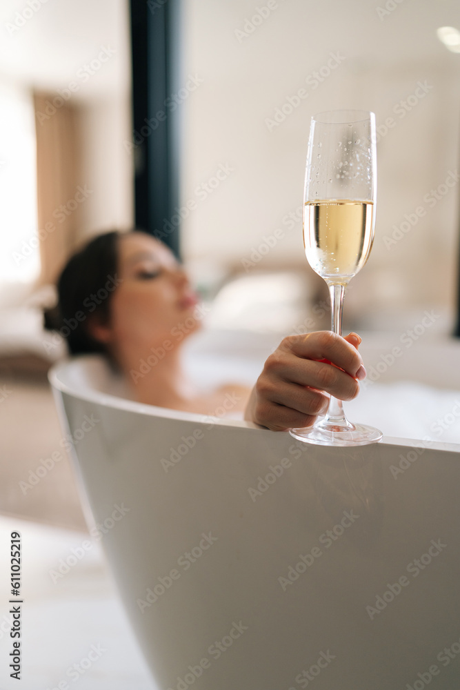 Vertical selective focus shot of young relaxed woman lying in foam bath ...