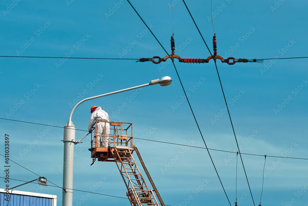 Painter in crane bucket paint street light pole. Worker in aerial ...