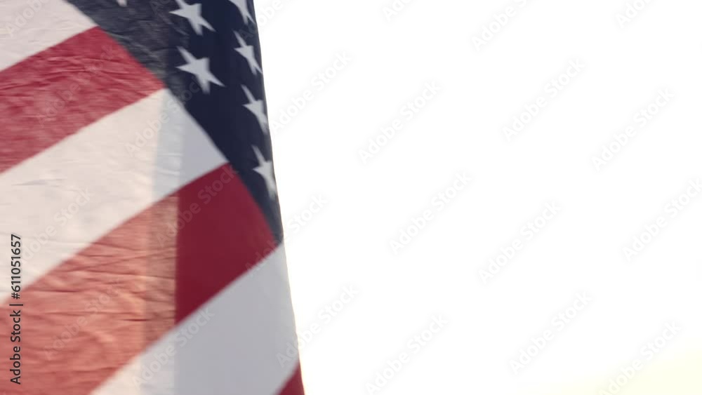 Close up the American flag is being waved against a backdrop of natural ...