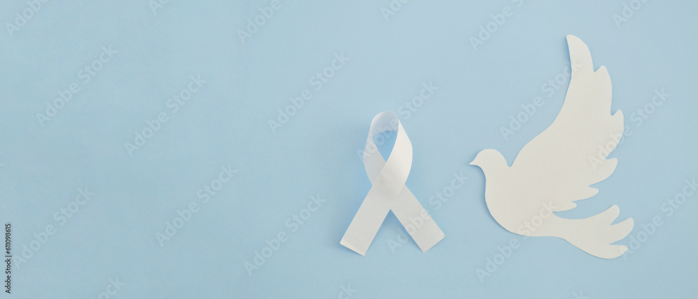 White ribbon as a symbol of peace and paper bird on blue background ...