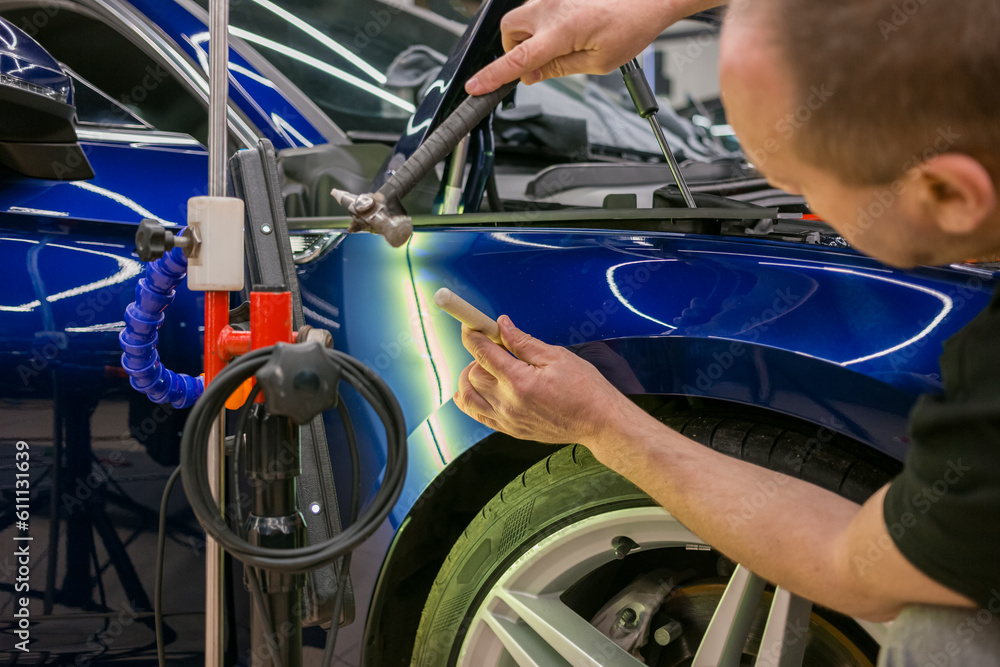 A specialist repairs a dent on the car body without painting. Process ...