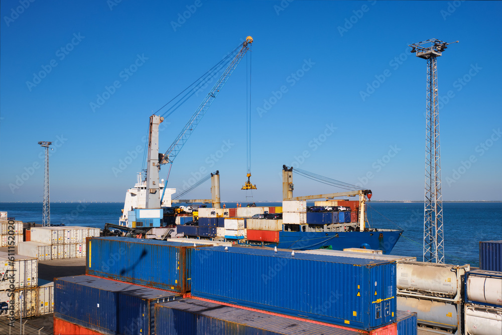 Port crane loading commercial container ship with cargo containers and ...