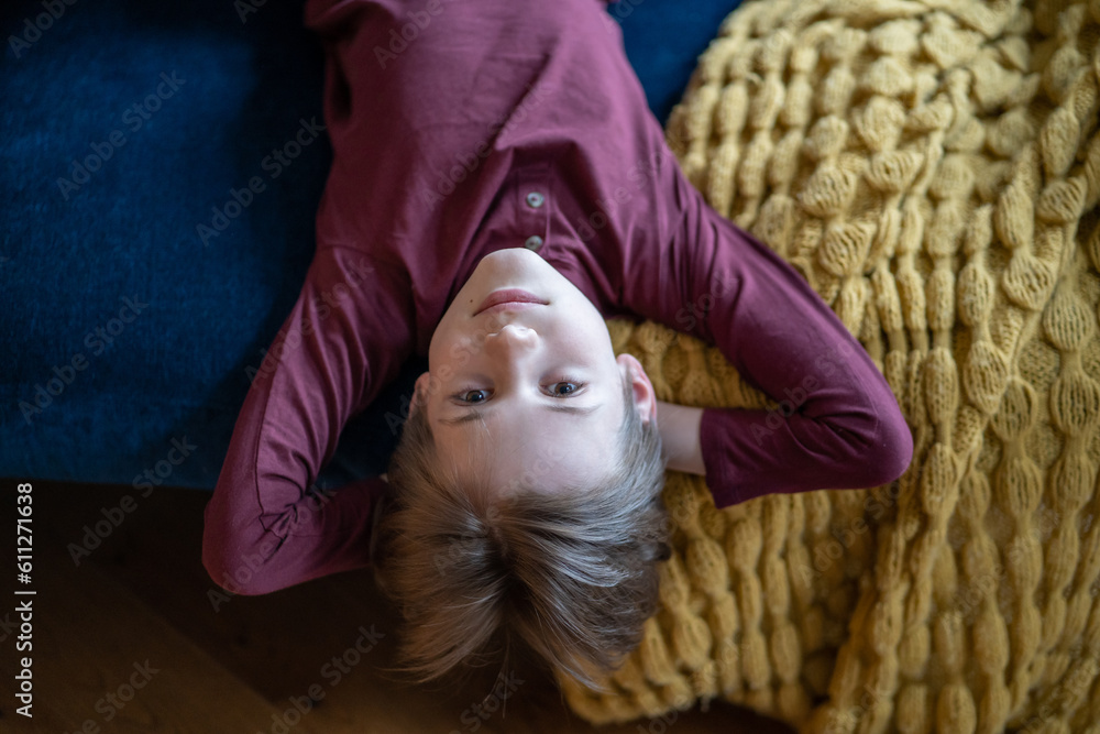 Portrait teenage boy lying on sofa upside down with hands behind head ...