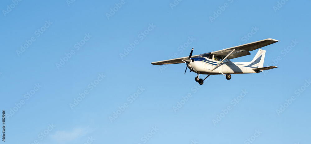 Small white plane with blue stripes of a cessna propeller flying in the ...